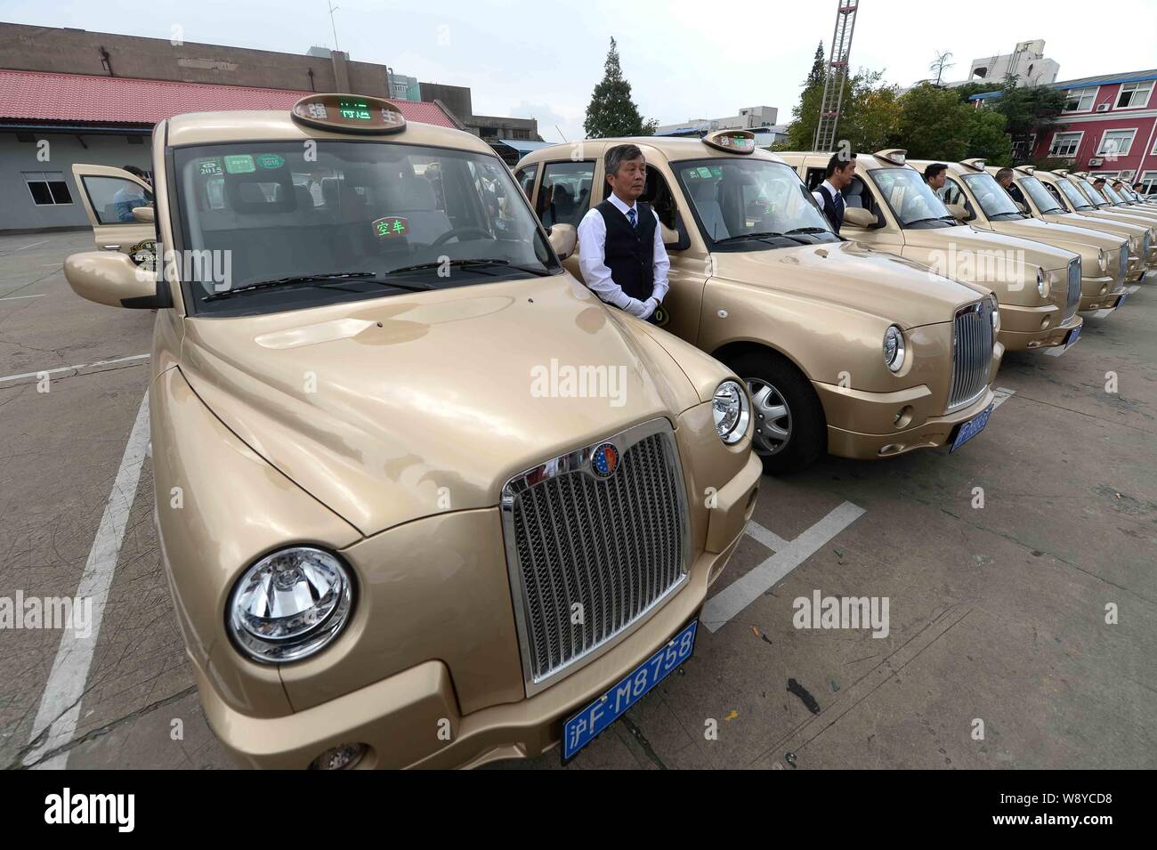Taxi drivers pose next to gold-painted London-style cabs at a parking ...