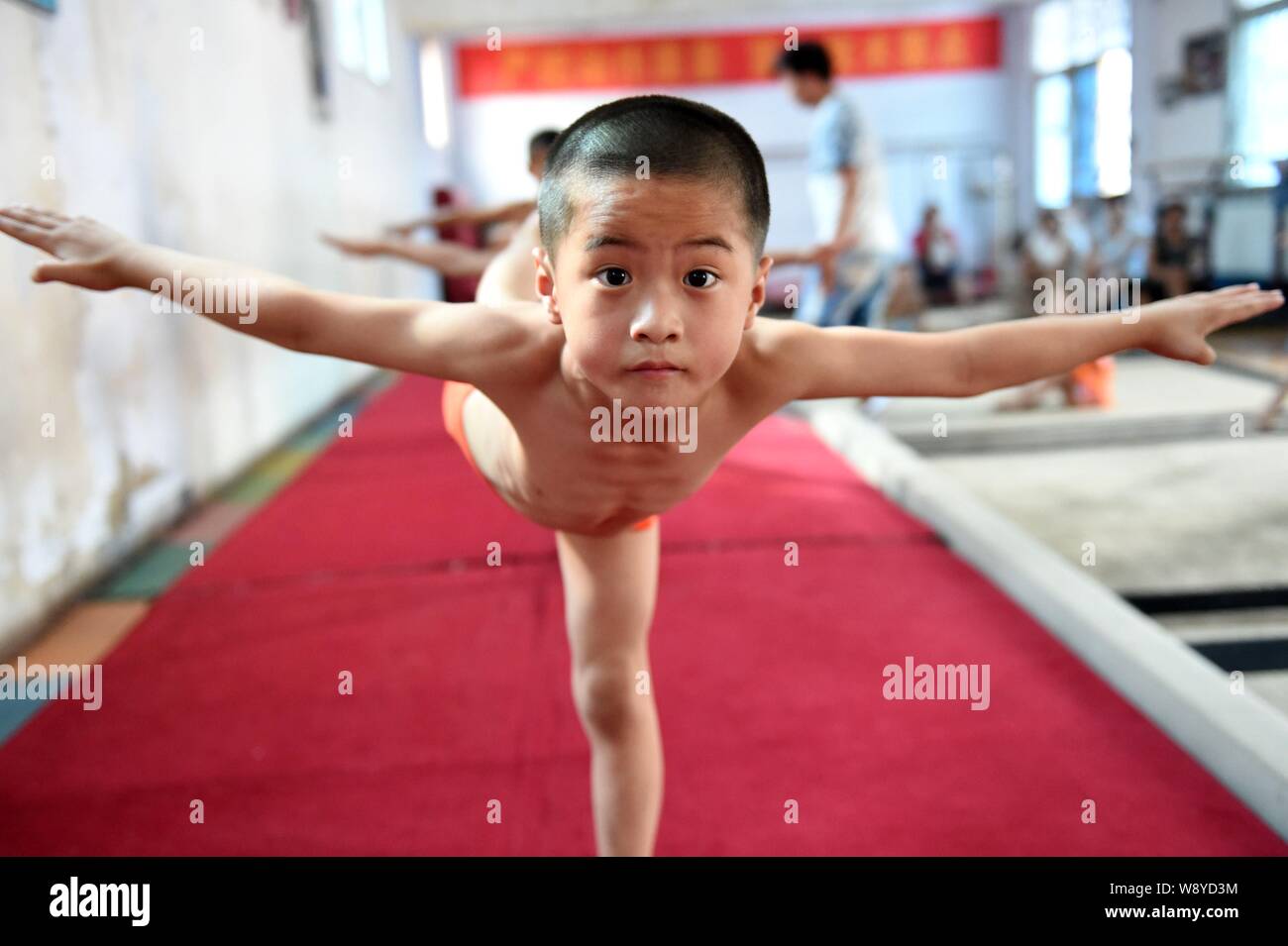 A young Chinese boy bends his body and stands on one leg to practice ...