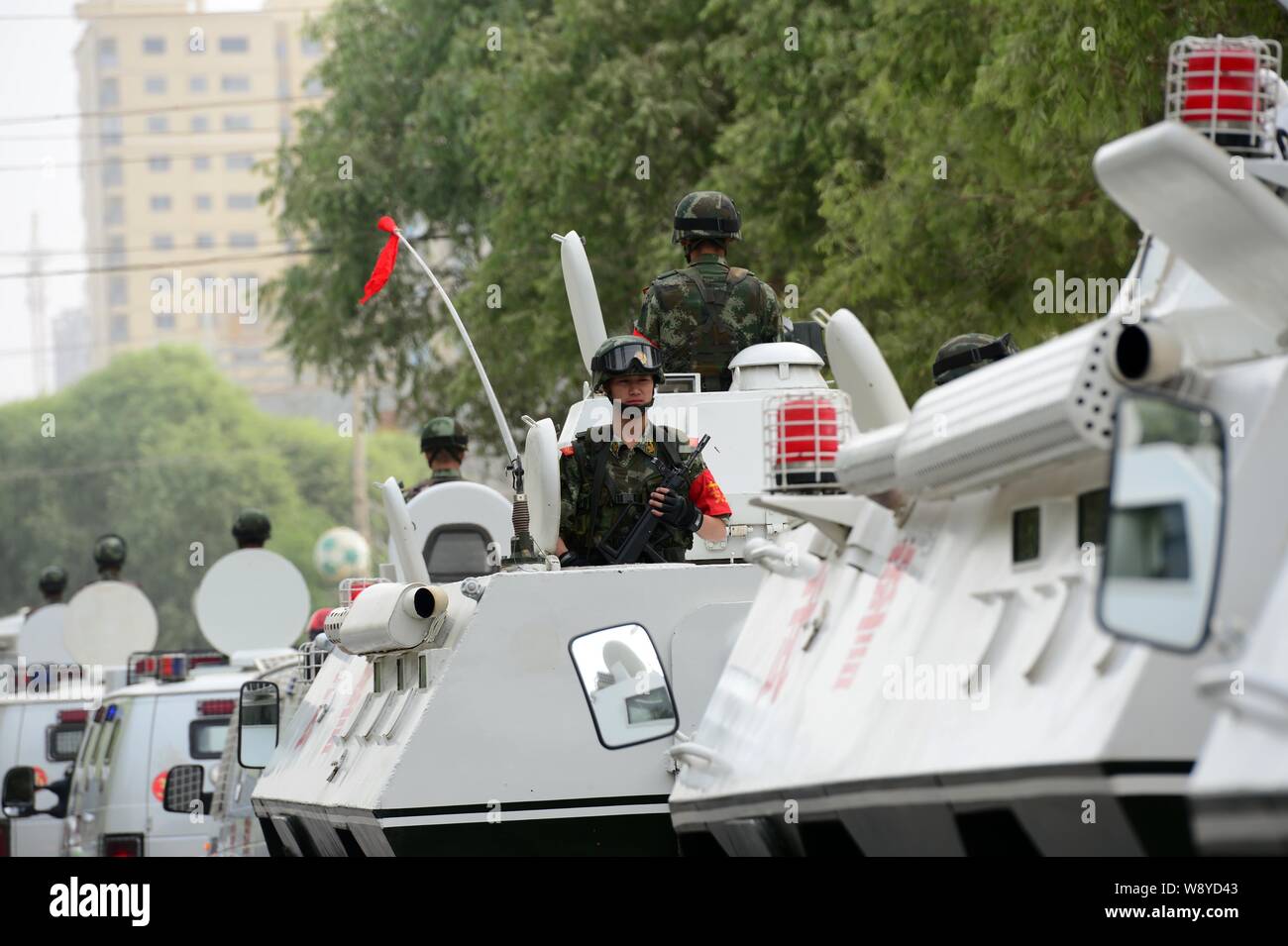 Armed Chinese paramilitary policemen stand on patrol vehicles during a ...