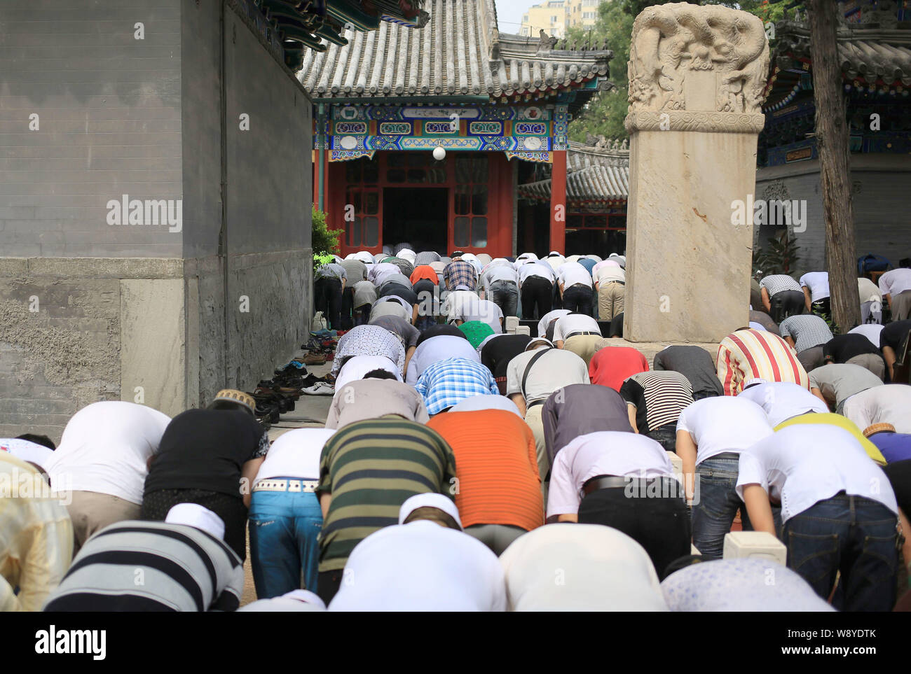 Chinese Muslims bow during an Eid al-Fitr morning prayer session at a ...