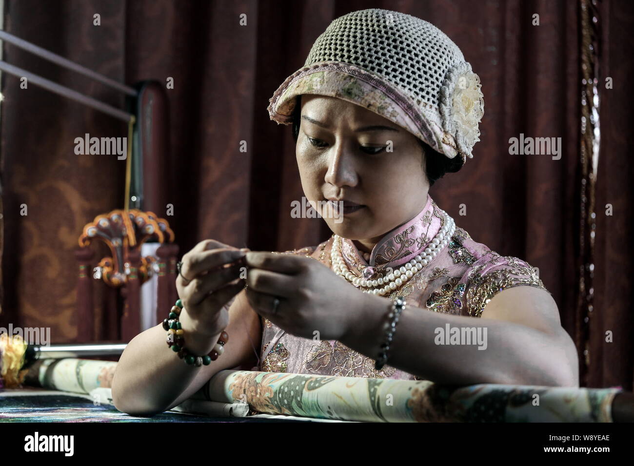35-year-old Yang Xiaoting threads a needle to stitch on her embroidery ...