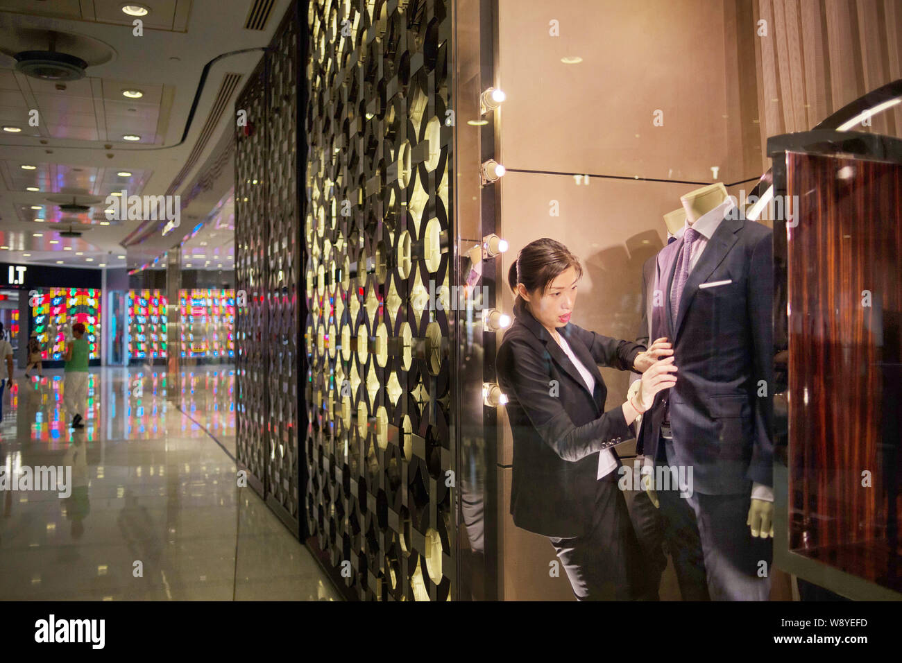A clerk adjusts a suit on display at a boutique of a shopping mall on ...