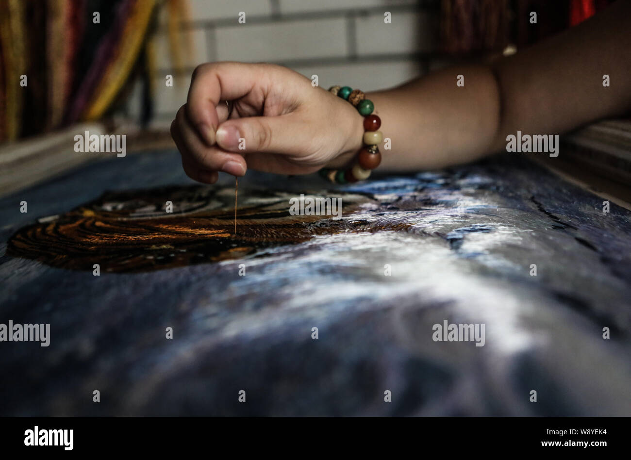 35-year-old Yang Xiaoting stitches on her embroidery work at her ...