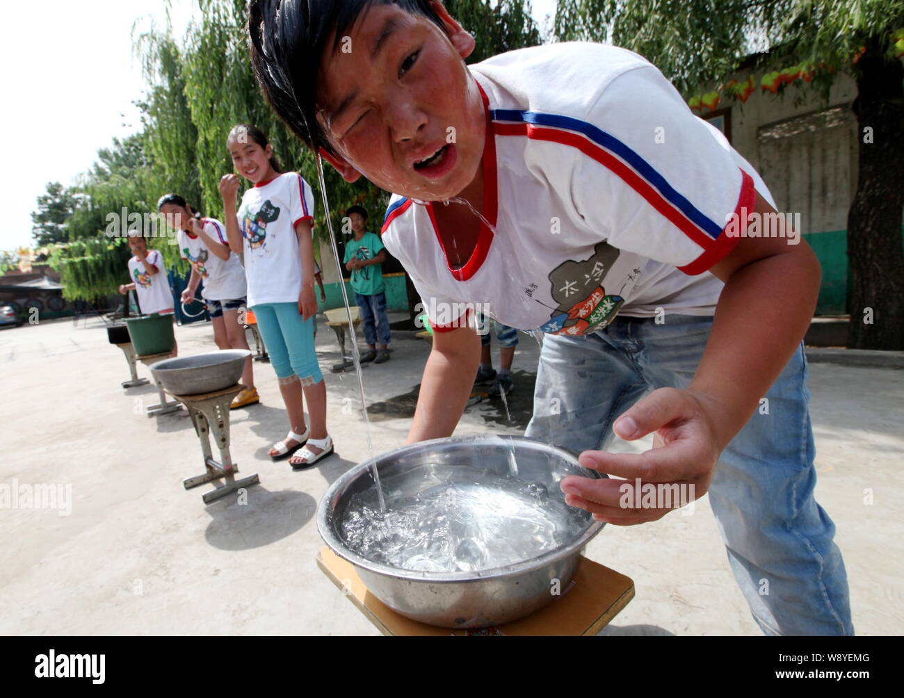 A young student gets wet after putting his head in a washbasin full of ...