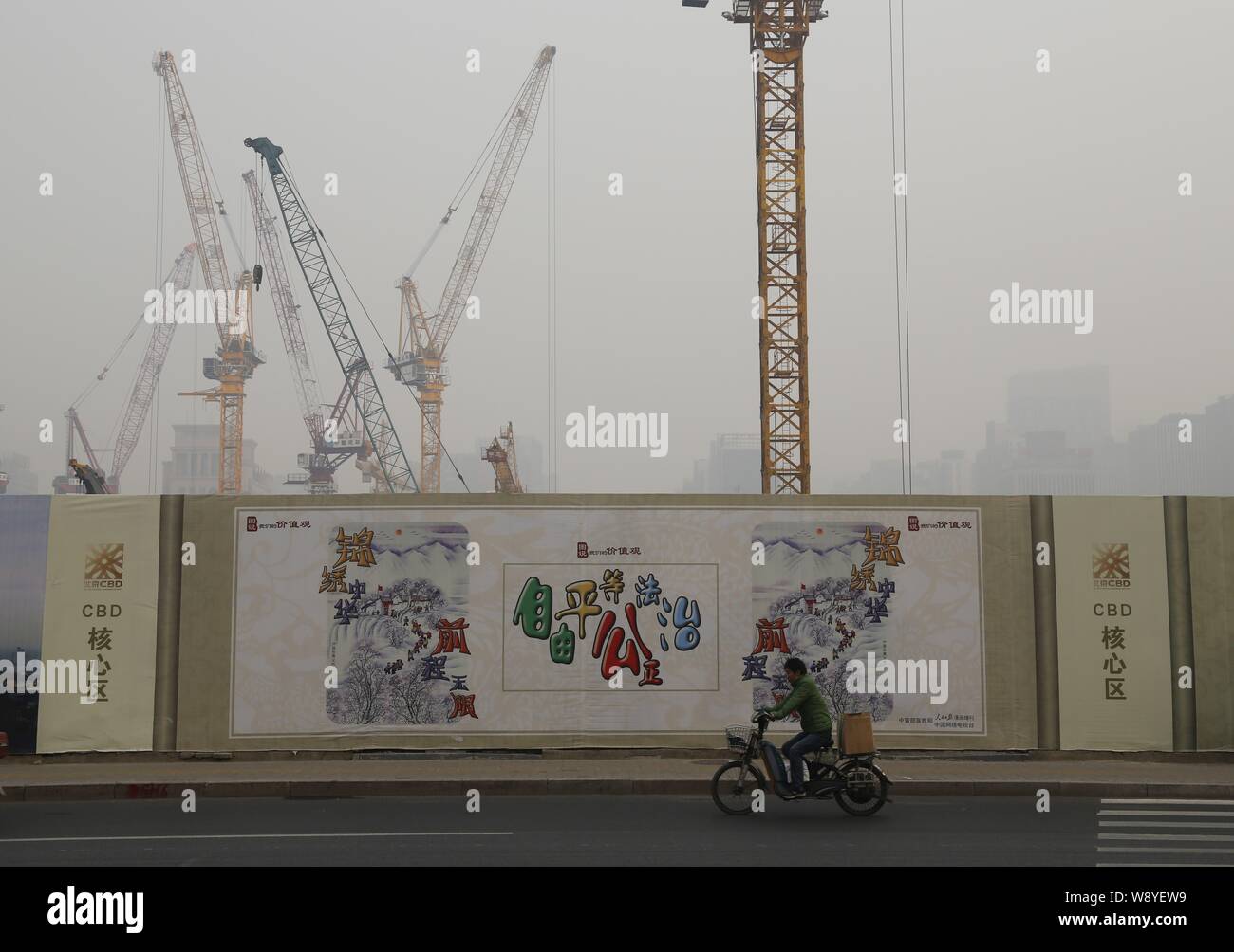 A cyclist rides his electric bike past a construction site in heavy ...
