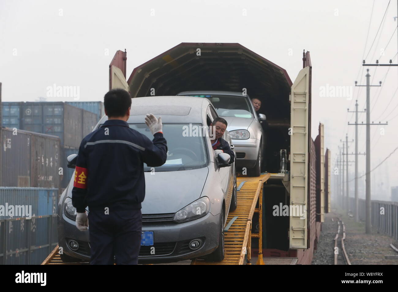 Workers drive cars out of a freight train at the Dahongmen Railway ...