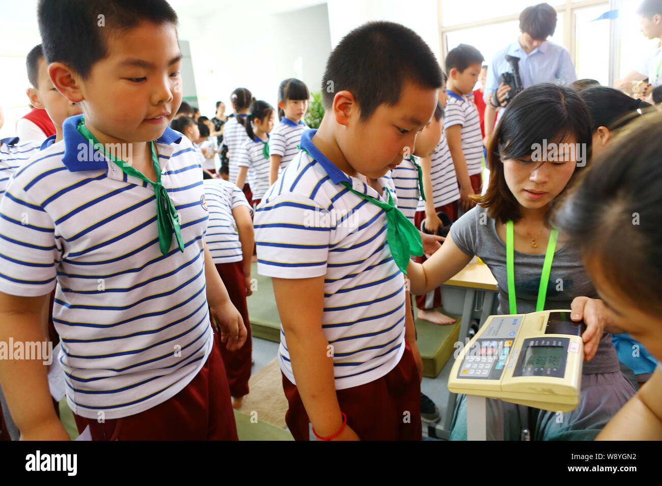Young students queue up to be weighed during a physical examination at ...