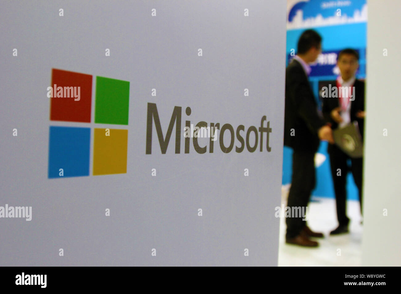 --FILE--Chinese employees are seen at the stand of Microsoft during the ...