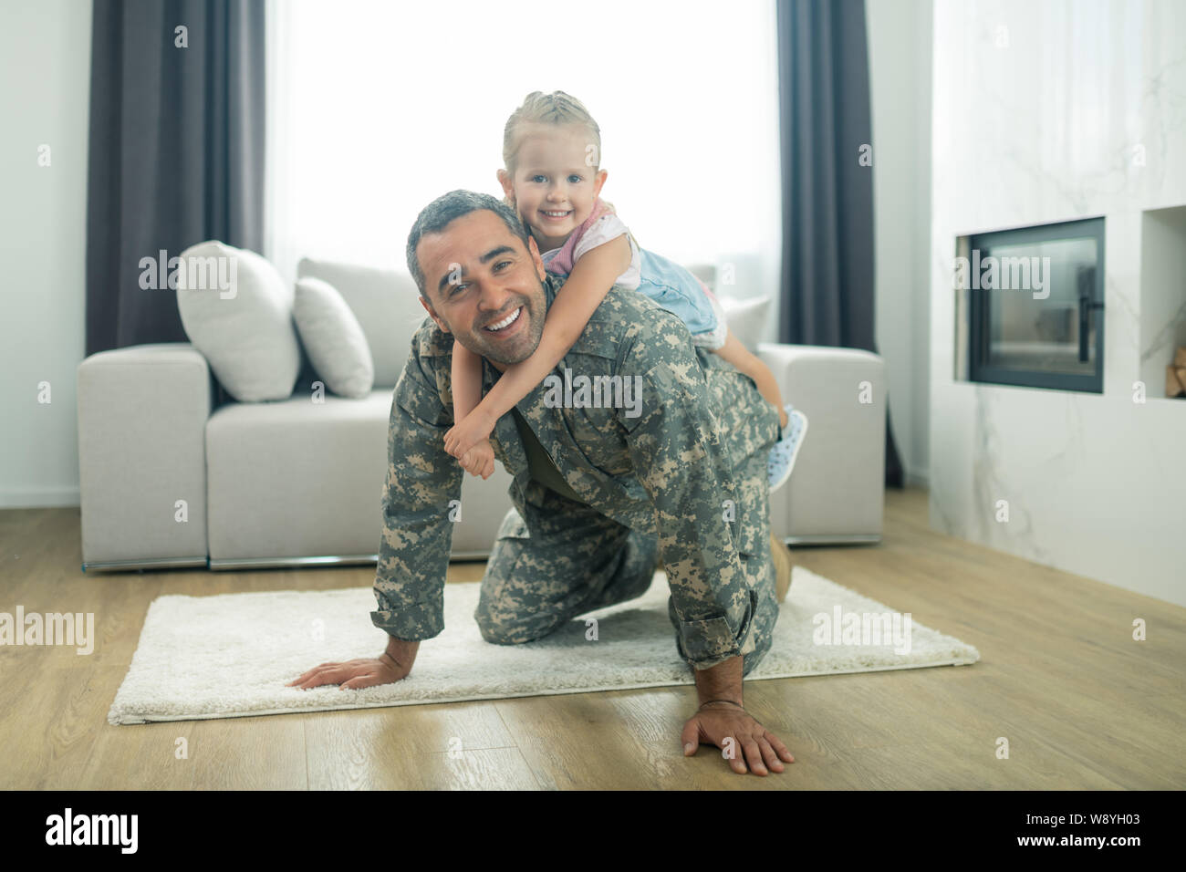 Lovely beaming girl sitting on back of father feeling happy Stock Photo ...