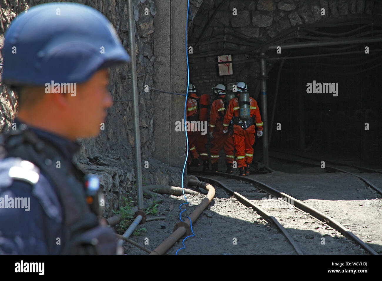 Rescuers walk into the coal mine as a police officer stands guard ...