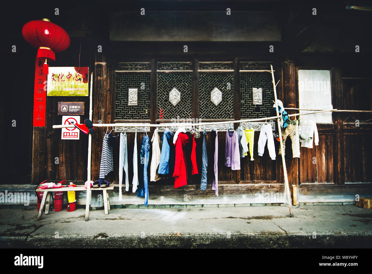 Local Chinese residents use a bamboo pole to air out clothes in front ...