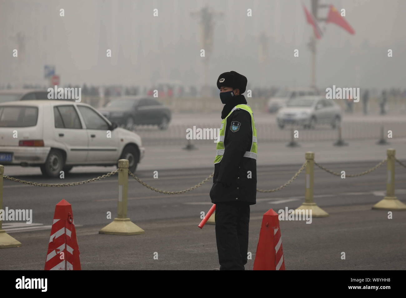 A Chinese security guard wearing a face mask stands on a road next to ...