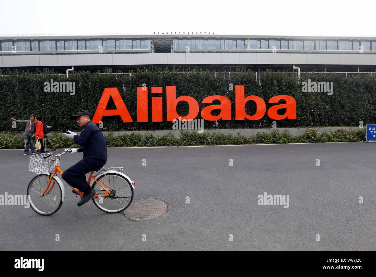 --FILE--A cyclist rides past the logo of Alibaba in front of the ...