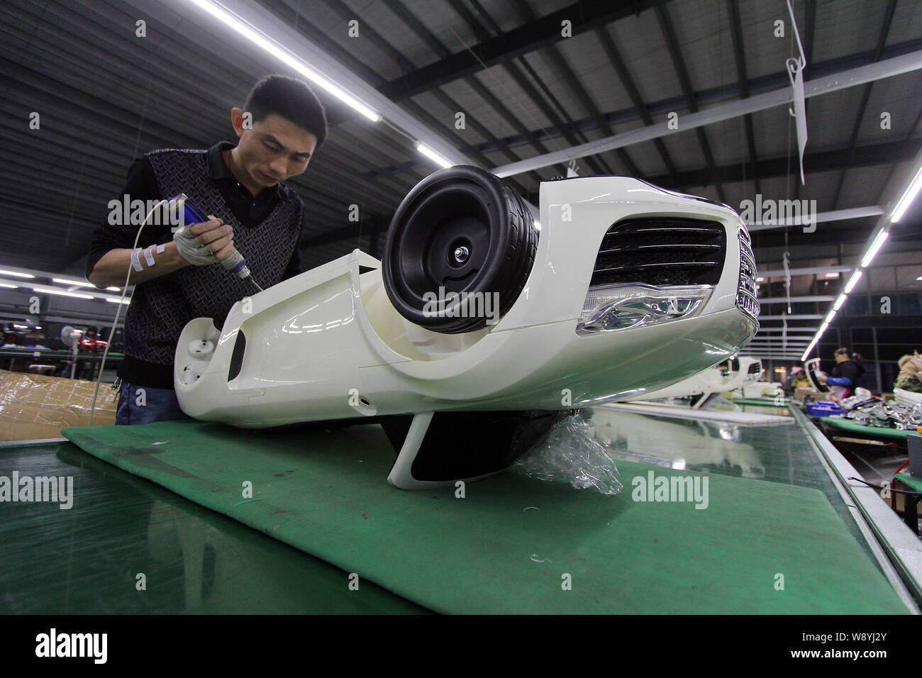 --FILE--A Chinese worker assembles an electric toy car on the ...