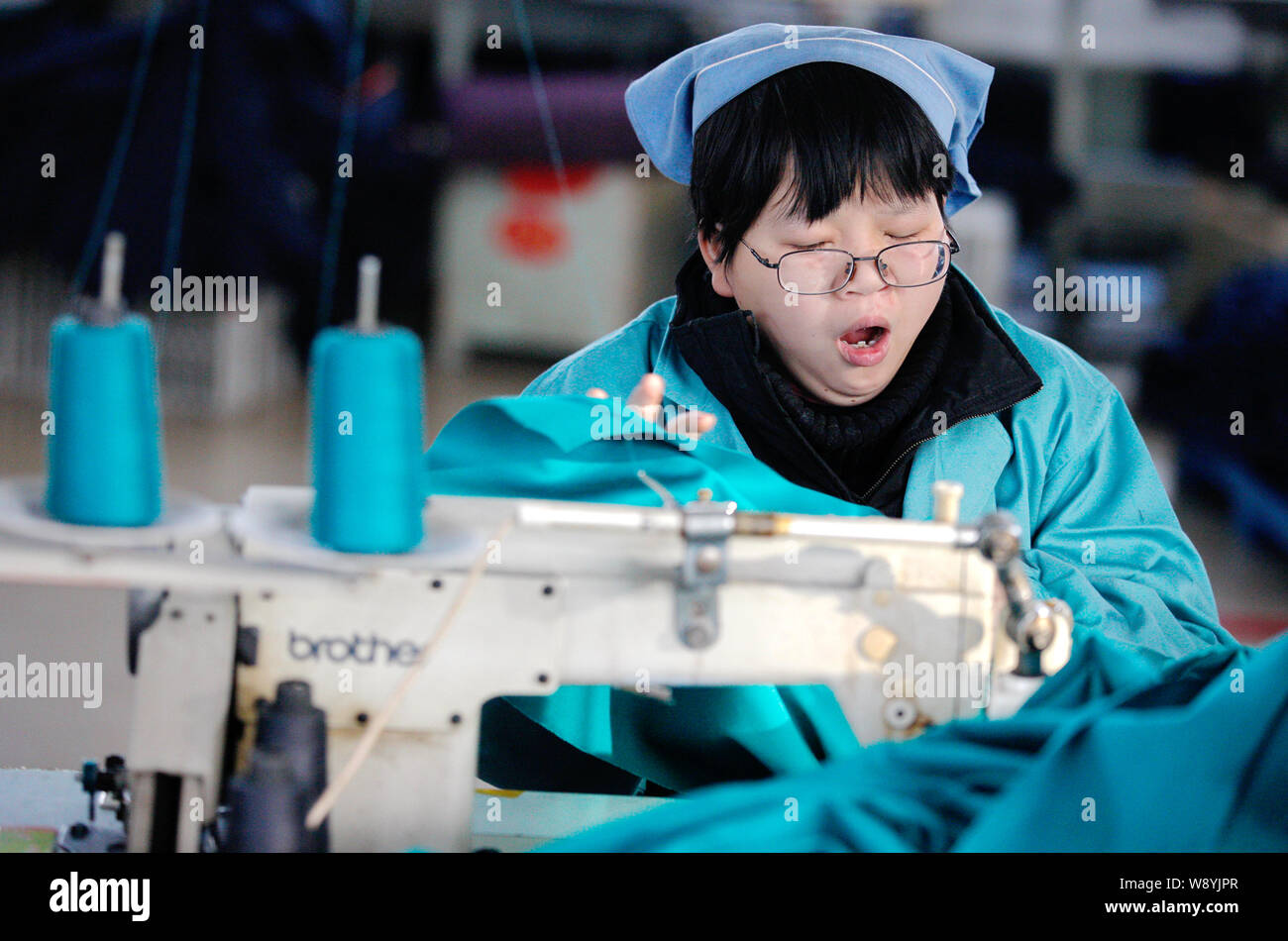 A female Chinese worker yawns as she sews clothes to be exported to the ...