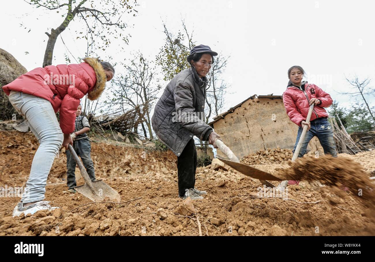 Two young girls help an elderly villager to level a plot for house ...