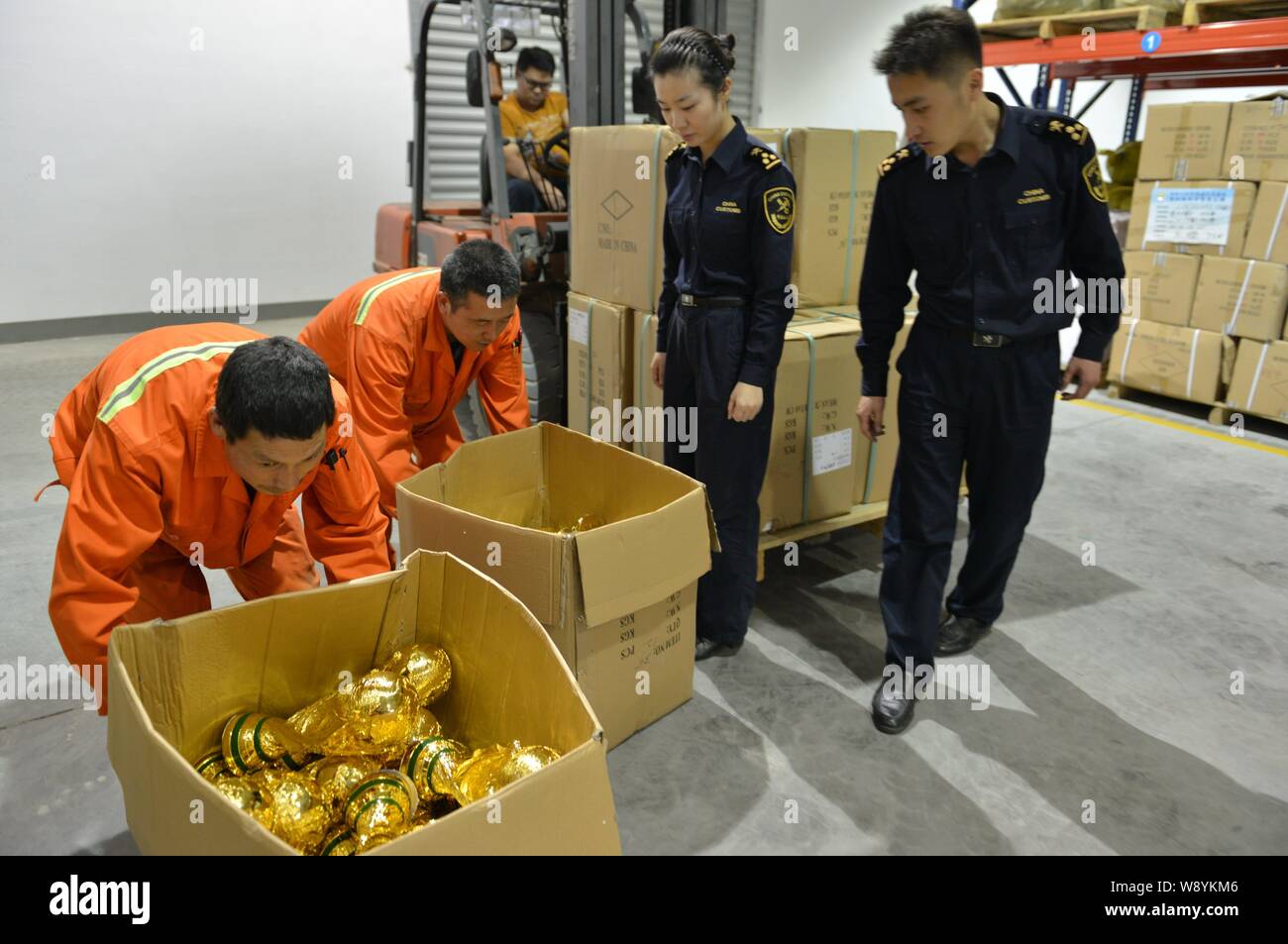 Chinese customs officers watch workers opening cartons full of fake ...