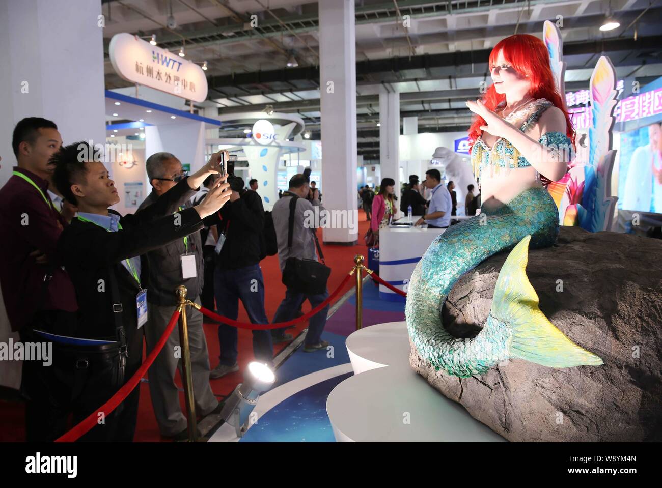 Visitors look at a mermaid robot on display during the 17th China ...
