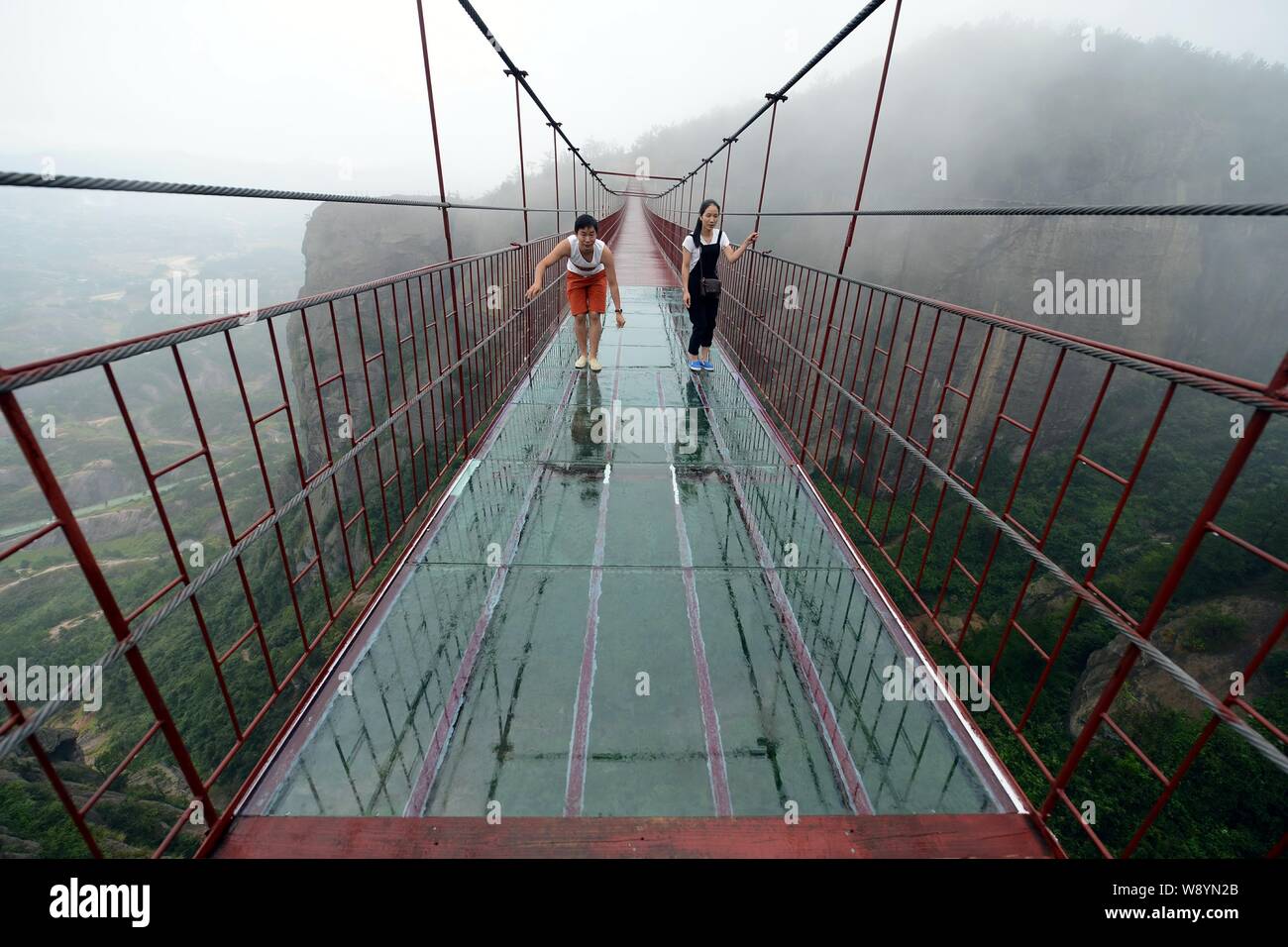 Tourists walk carefully on a 300-meter long plexiglass bridge which ...