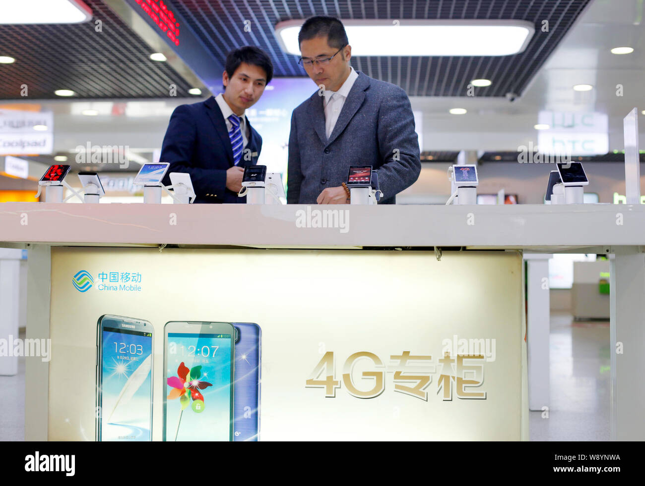 --FILE--A Chinese customer tries out 4G supported smartphones at a ...
