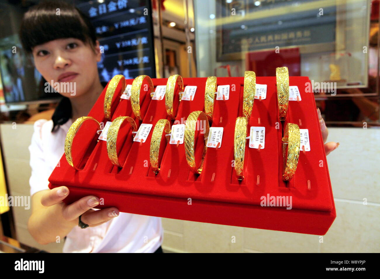 A Chinese clerk shows gold bracelets at a jewelry store in Lianyungang ...