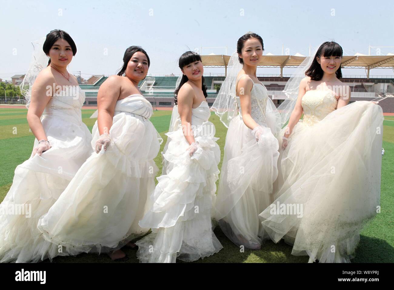 Female students wearing bridal wedding dresses pose for their ...