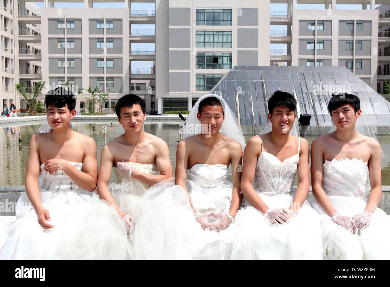 Male students wearing bridal wedding dresses pose for their graduation ...