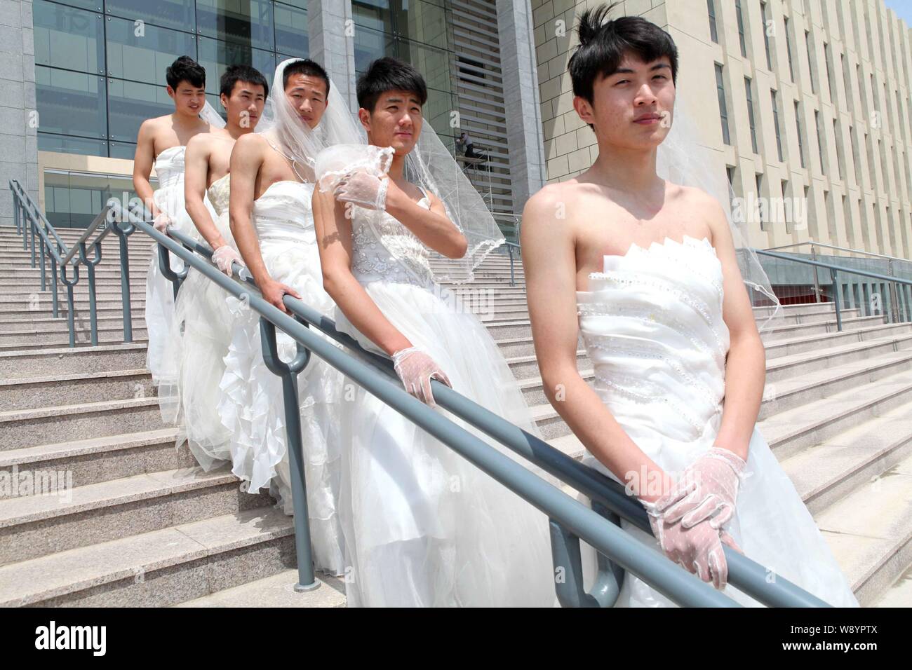 Male students wearing bridal wedding dresses pose for their graduation ...