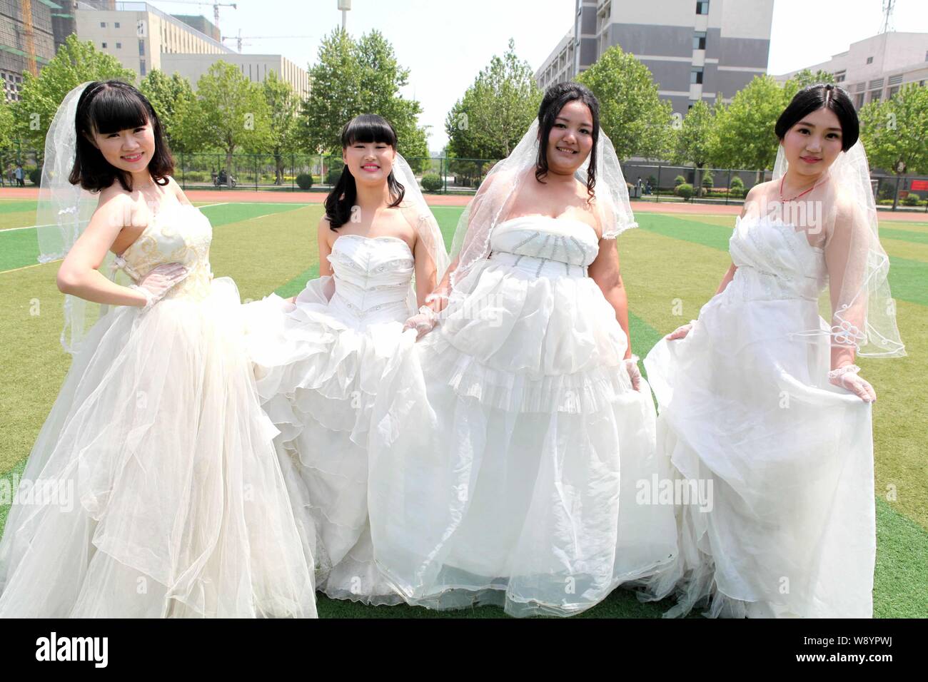 Female students wearing bridal wedding dresses pose for their ...