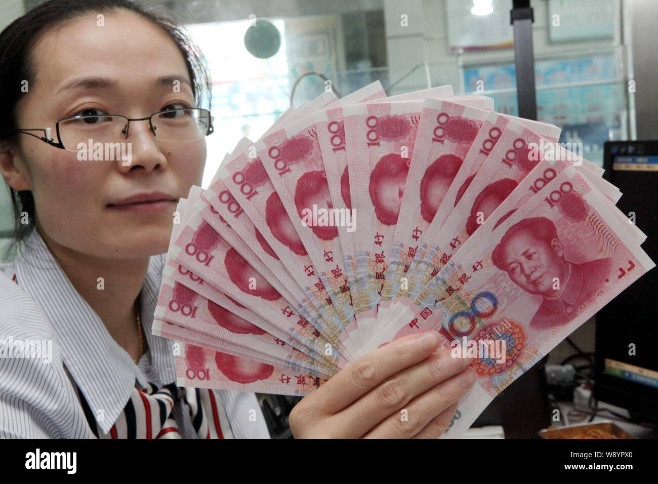 --FILE--A Chinese clerk shows RMB (renminbi) yuan banknotes at a bank ...