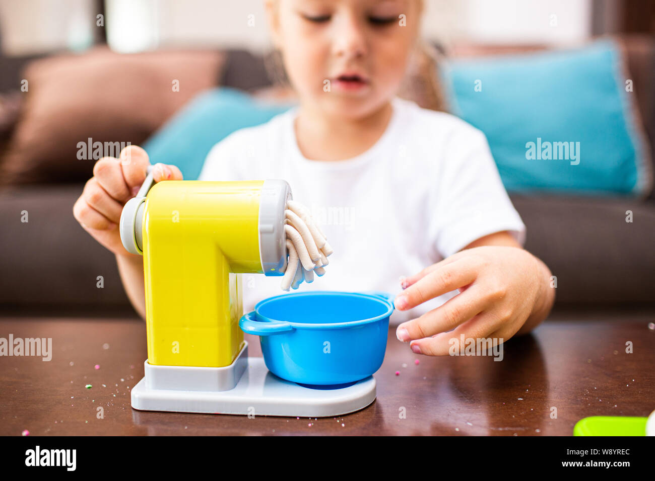 Little blonde girl playing modeling plasticine or molding clay. Gigl ...