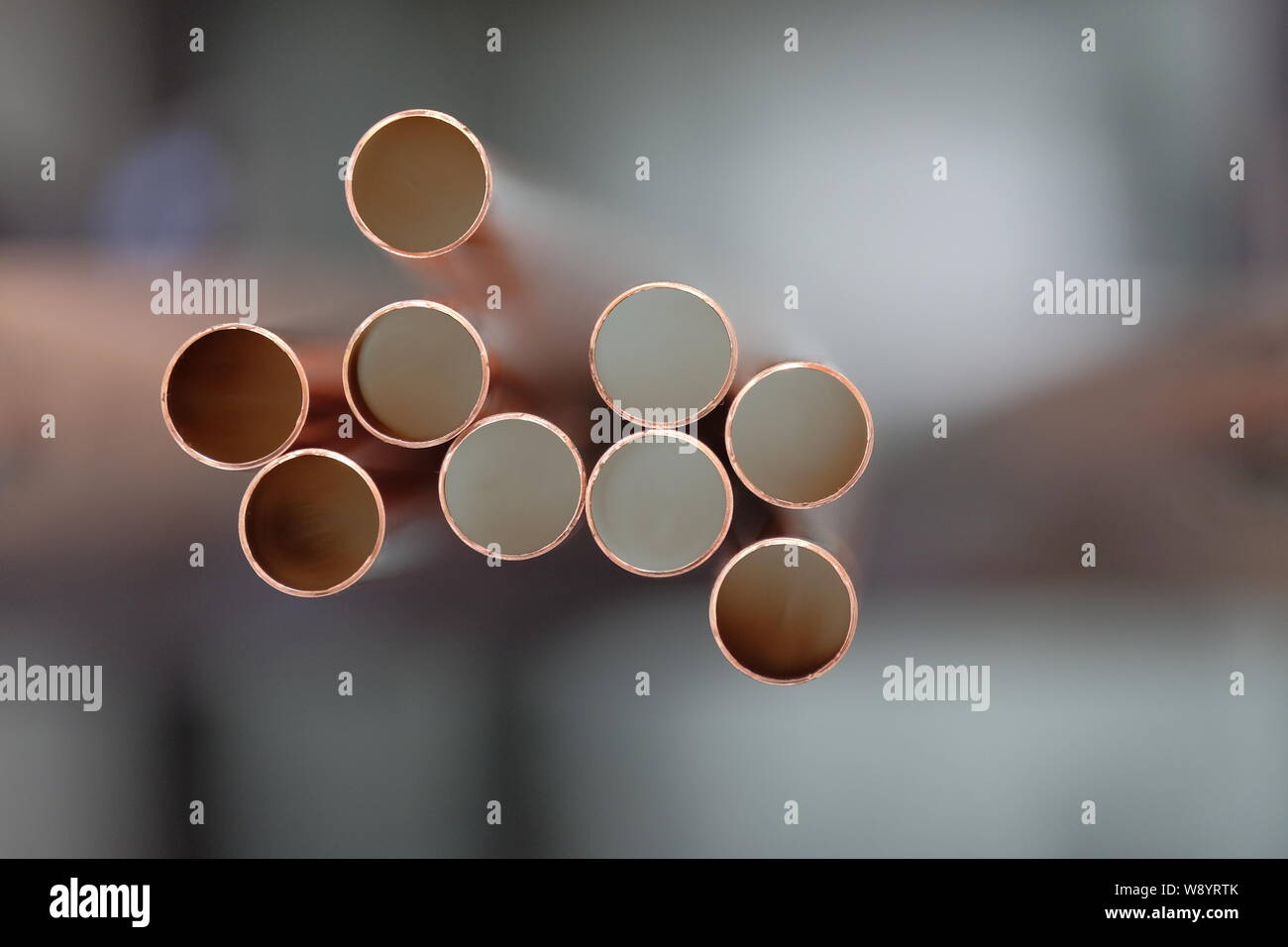 Side-view of nine (9) copper pipes on a blue background with a shallow ...