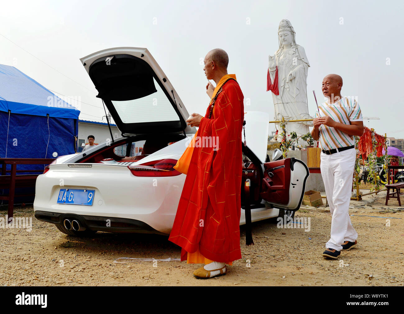 A Chinese Buddhist monk blesses a Porsche sports car during a great ...