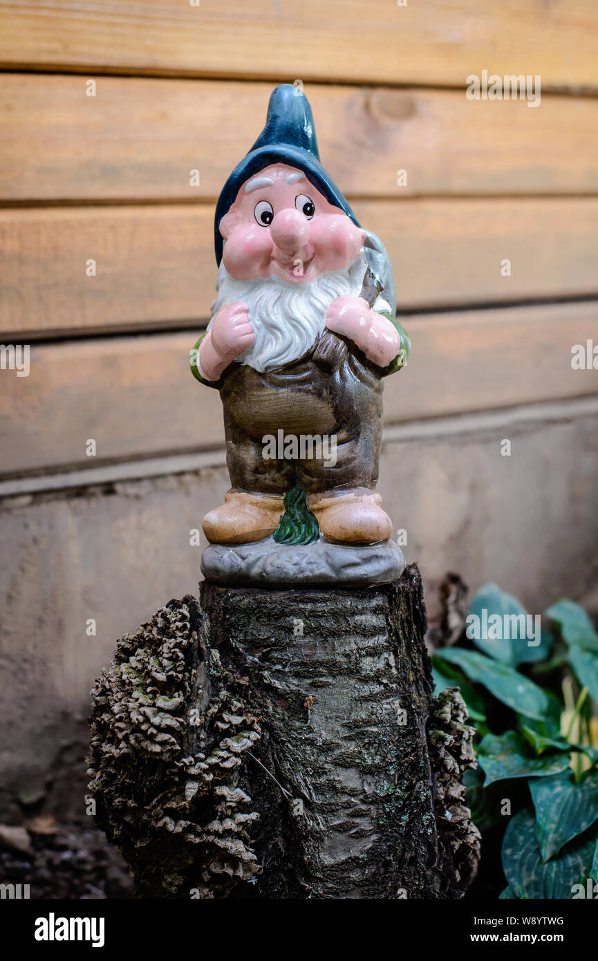 Figurine of a funny dwarf in the garden on a stump on a wooden ...