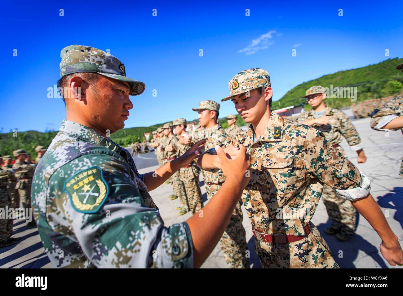 A Chinese drillmaster adjusts the posture of a student during a ...