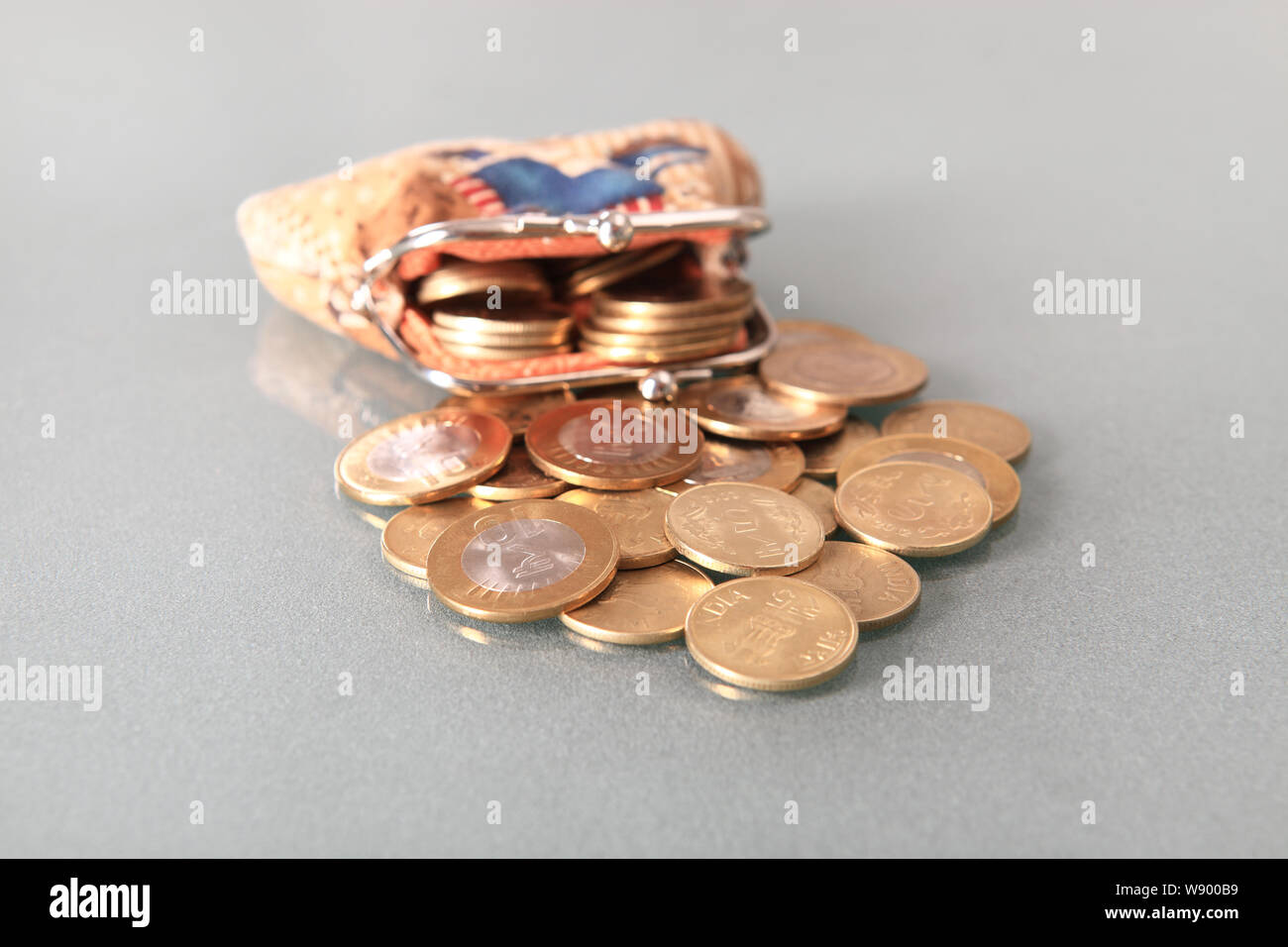 Coins spilling out of purse Stock Photo - Alamy