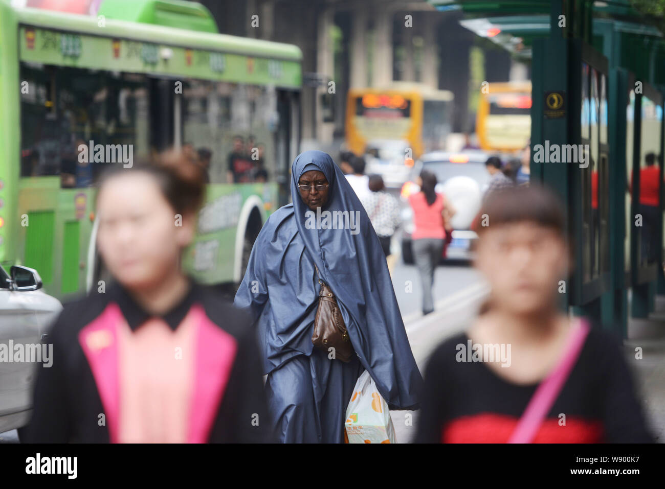 An African woman, back, and local Chinese residents walk on a road at ...