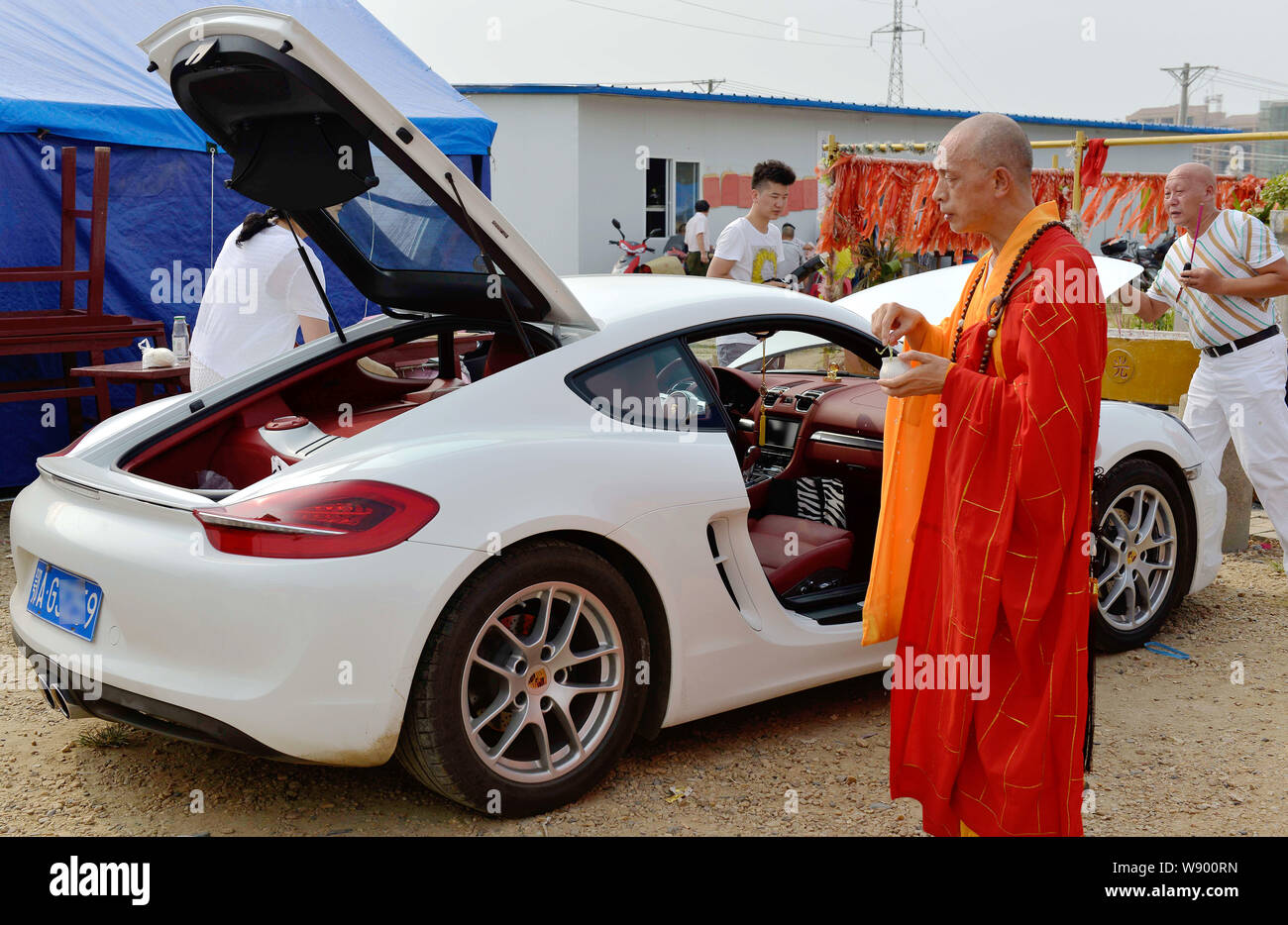 A Chinese Buddhist monk blesses a Porsche sports car during a great ...