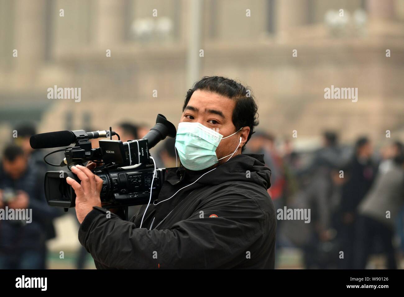 A reporter wearing a face mask takes videos in heavy smog outside the ...