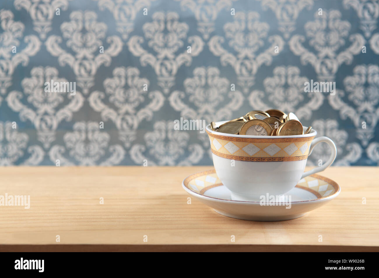 Coins in a tea cup Stock Photo - Alamy