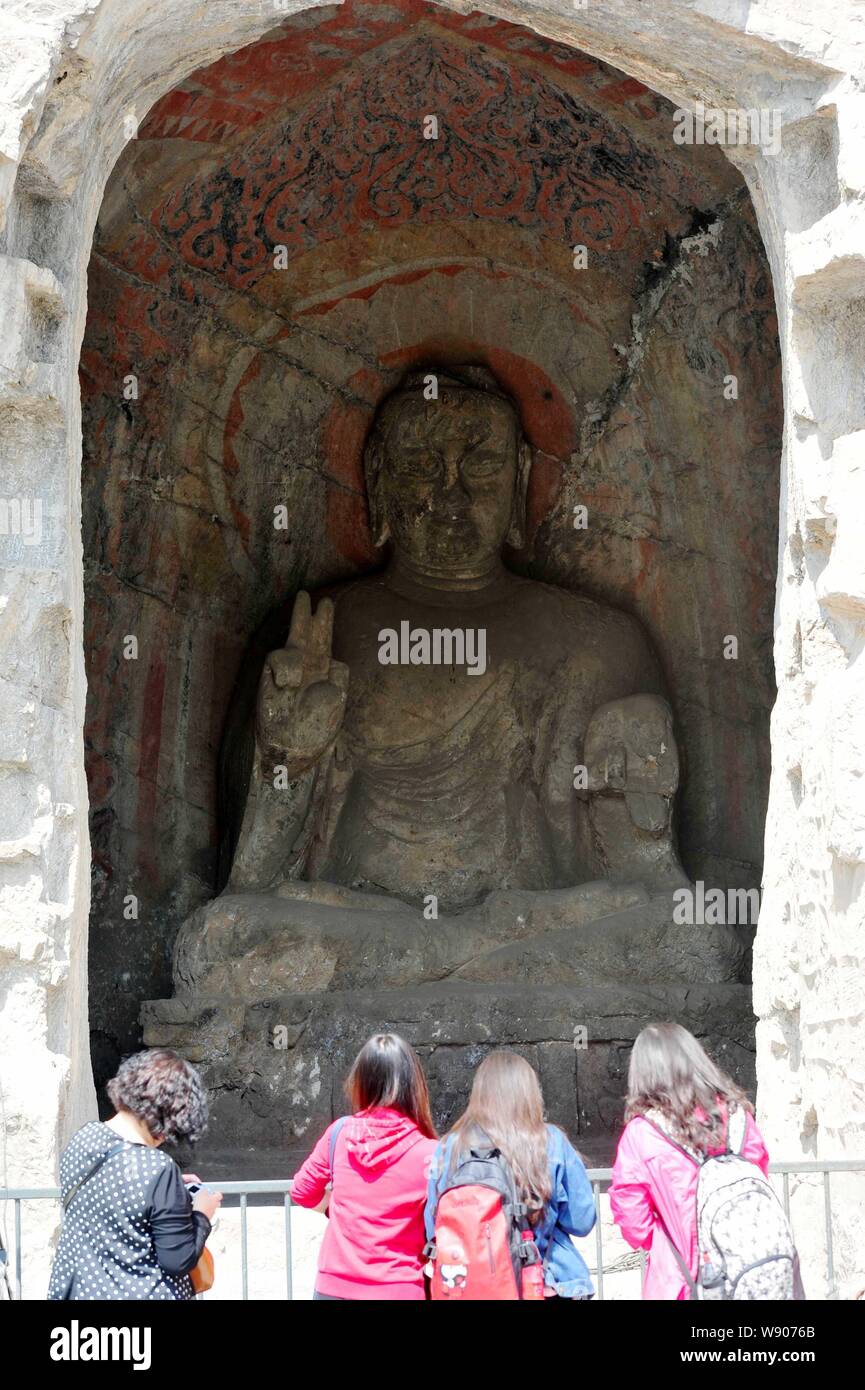 Tourists visit the 104th cave to view the stone Amita Buddha statue ...