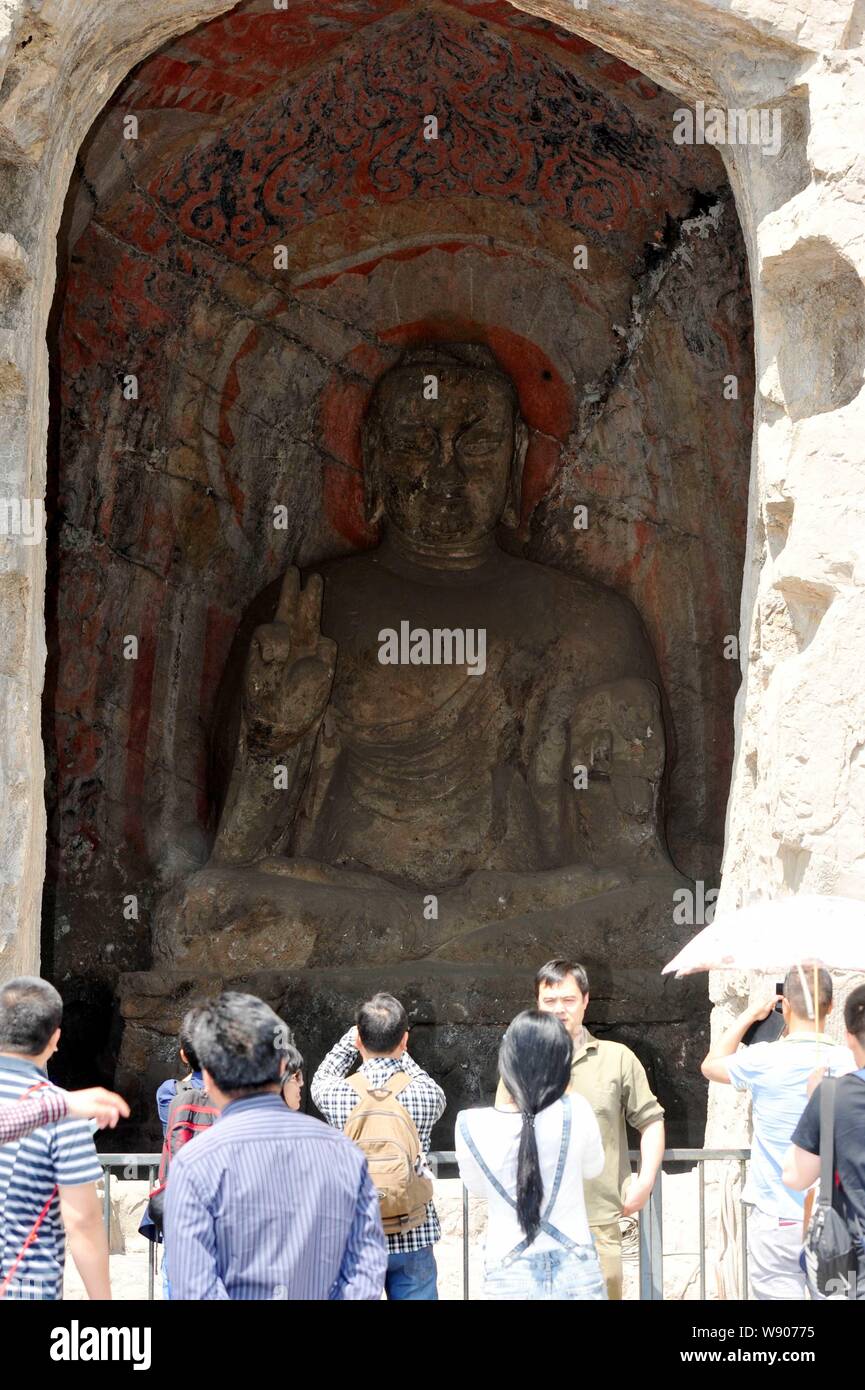Tourists visit the 104th cave to view the stone Amita Buddha statue ...