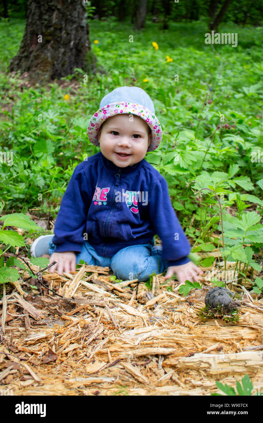 Cheerful girl in a hat exploring fallen trees in the forest. Baby 9 ...