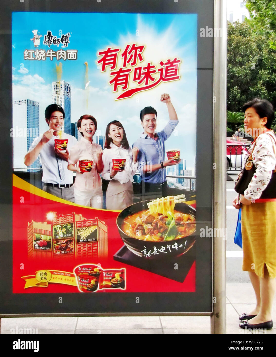 --FILE--A passenger stands next to an advertisement for Master Kong ...