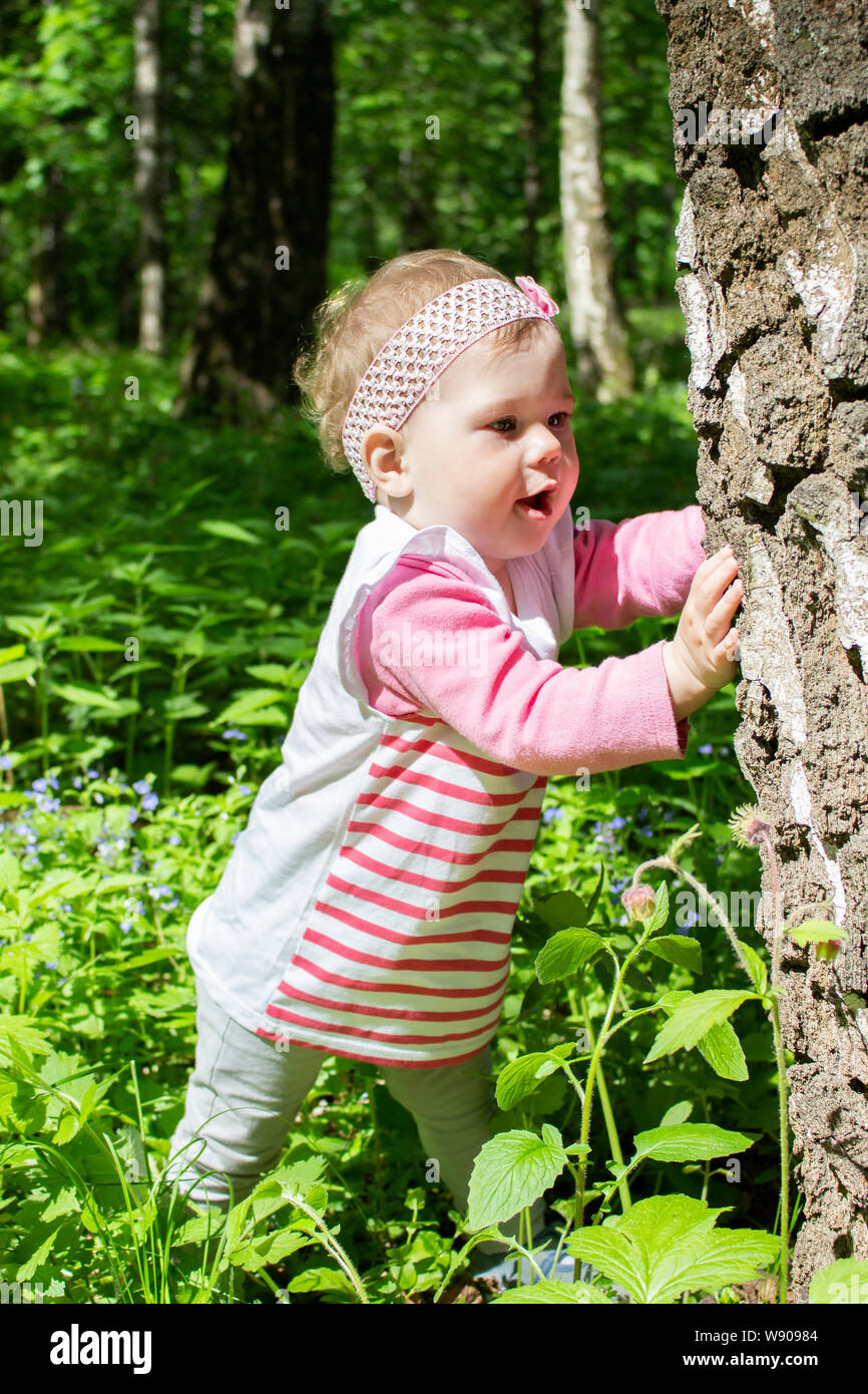 A young child exploring a tree trunk with a surprised face with open ...