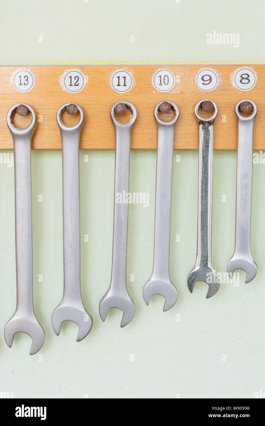 collection of spanners hanging on the wall on a wooden holder Stock ...