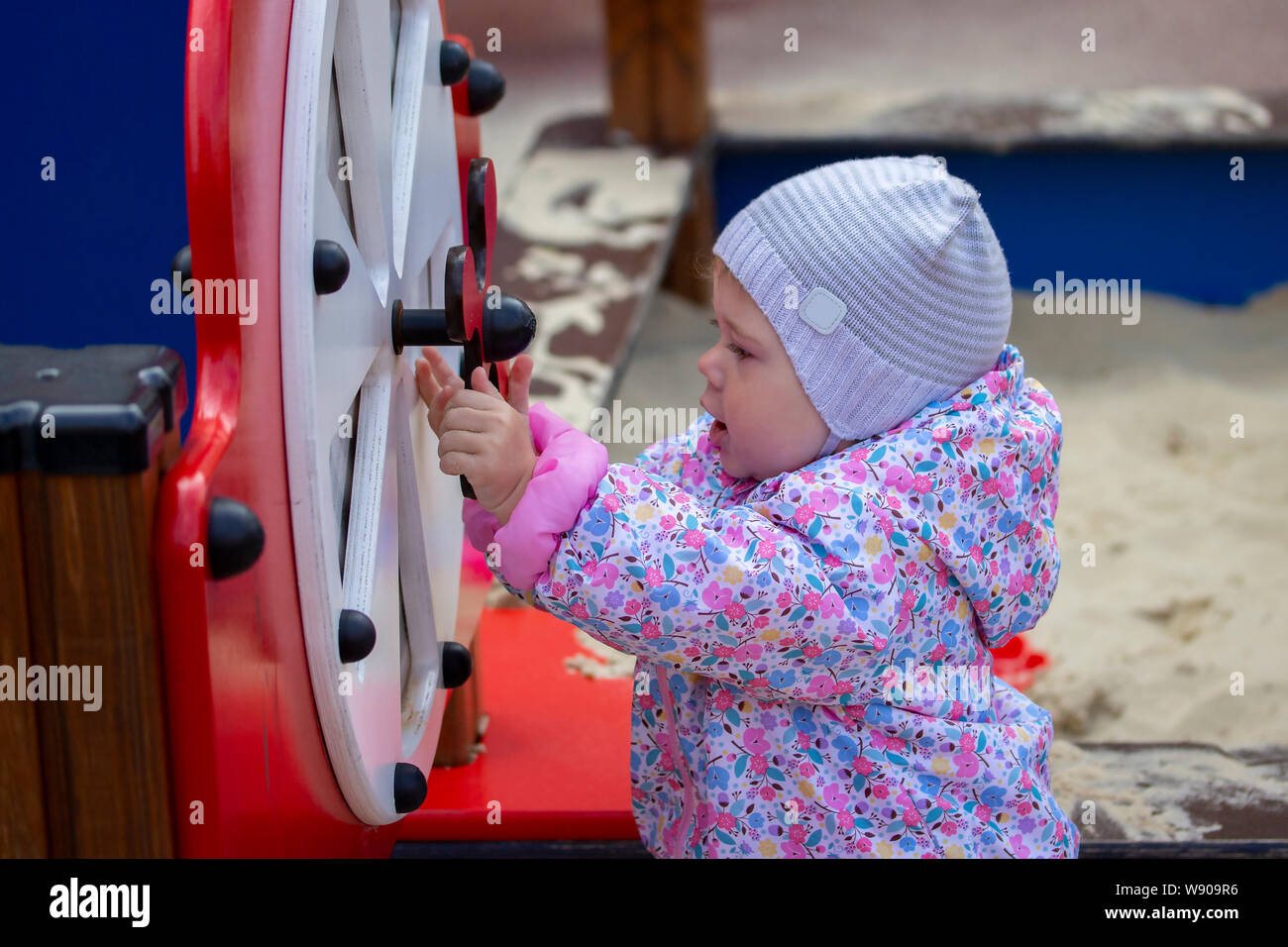 Baby girl spinning a toy wheel in the playground. The girl plays in the ...