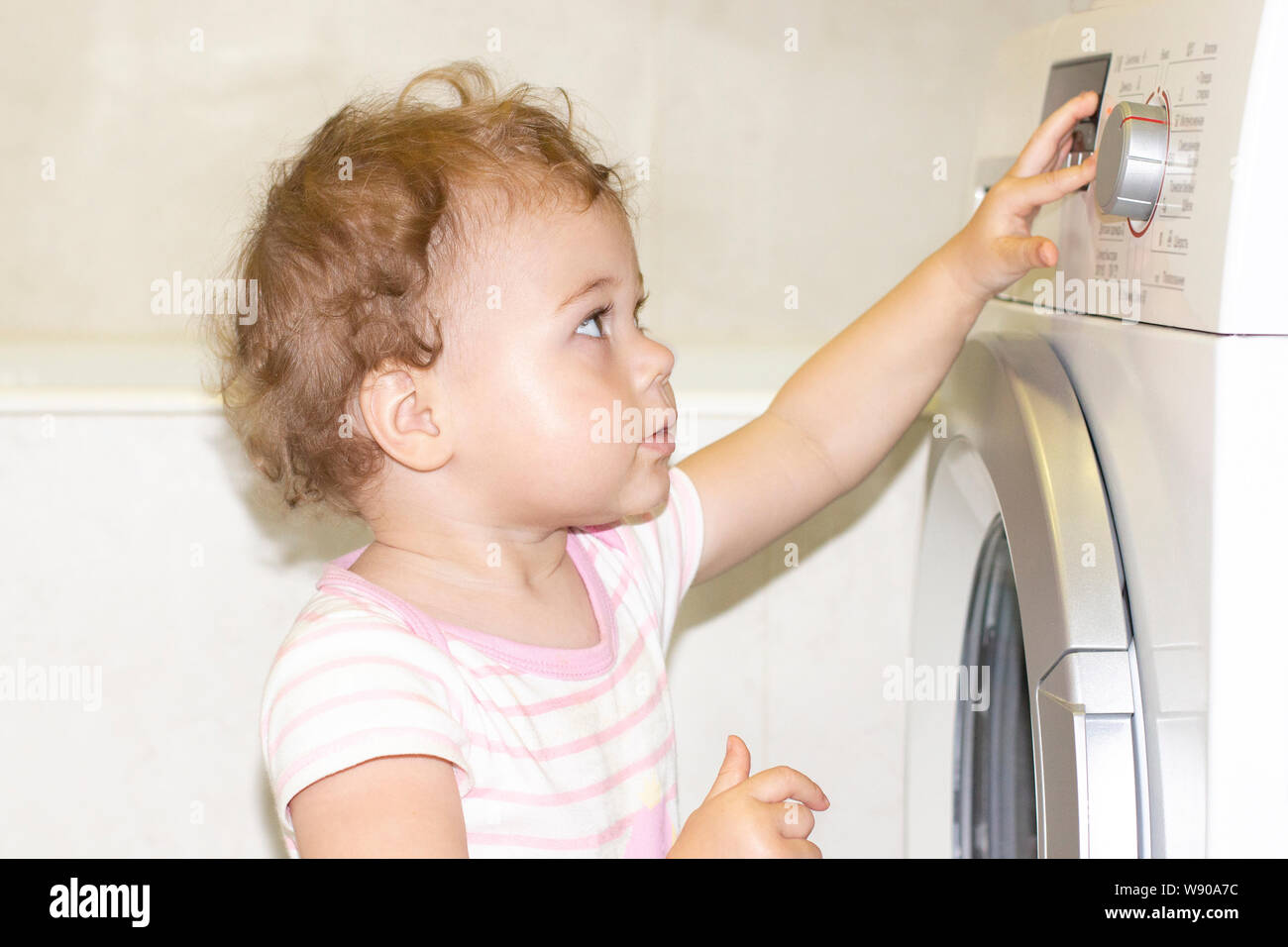 Little baby girl 1 year old presses the buttons on the washing machine ...