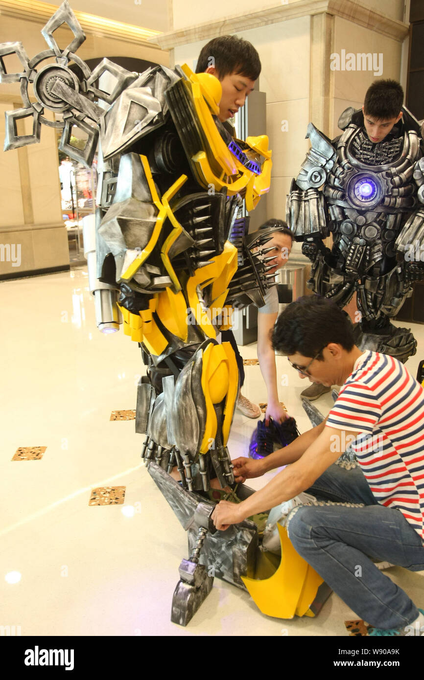 A staff member helps a performer put on his Transformers costume during ...