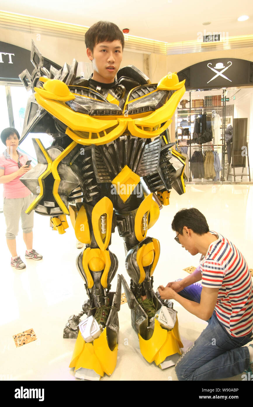 A staff member helps a performer put on his Transformers costume during ...